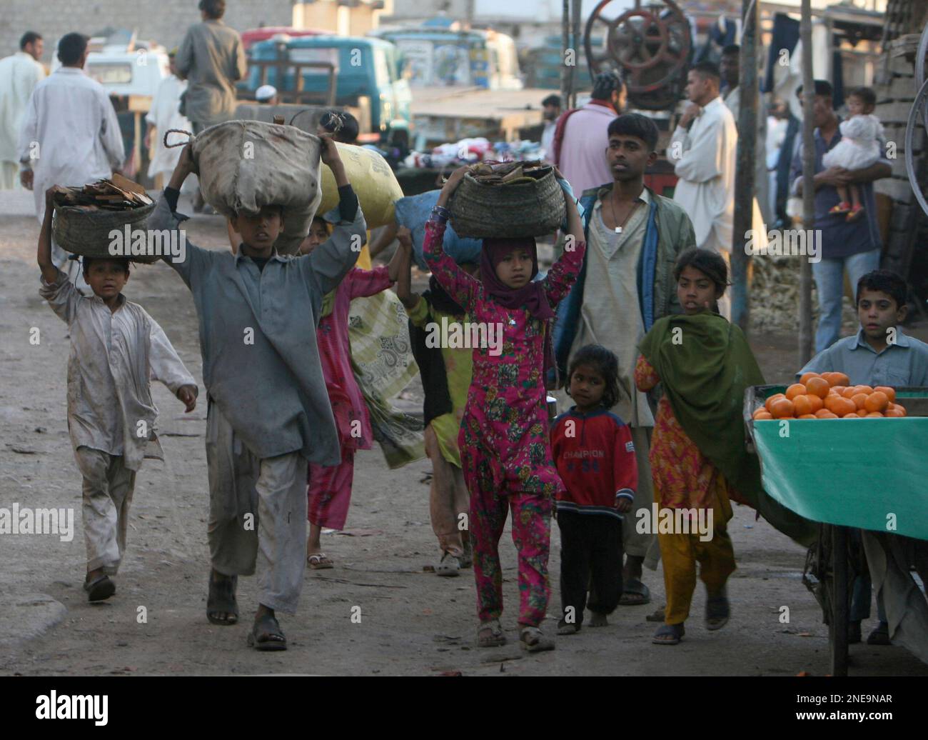 Pakistani poor children carry pieces of wood for cooking they collected ...