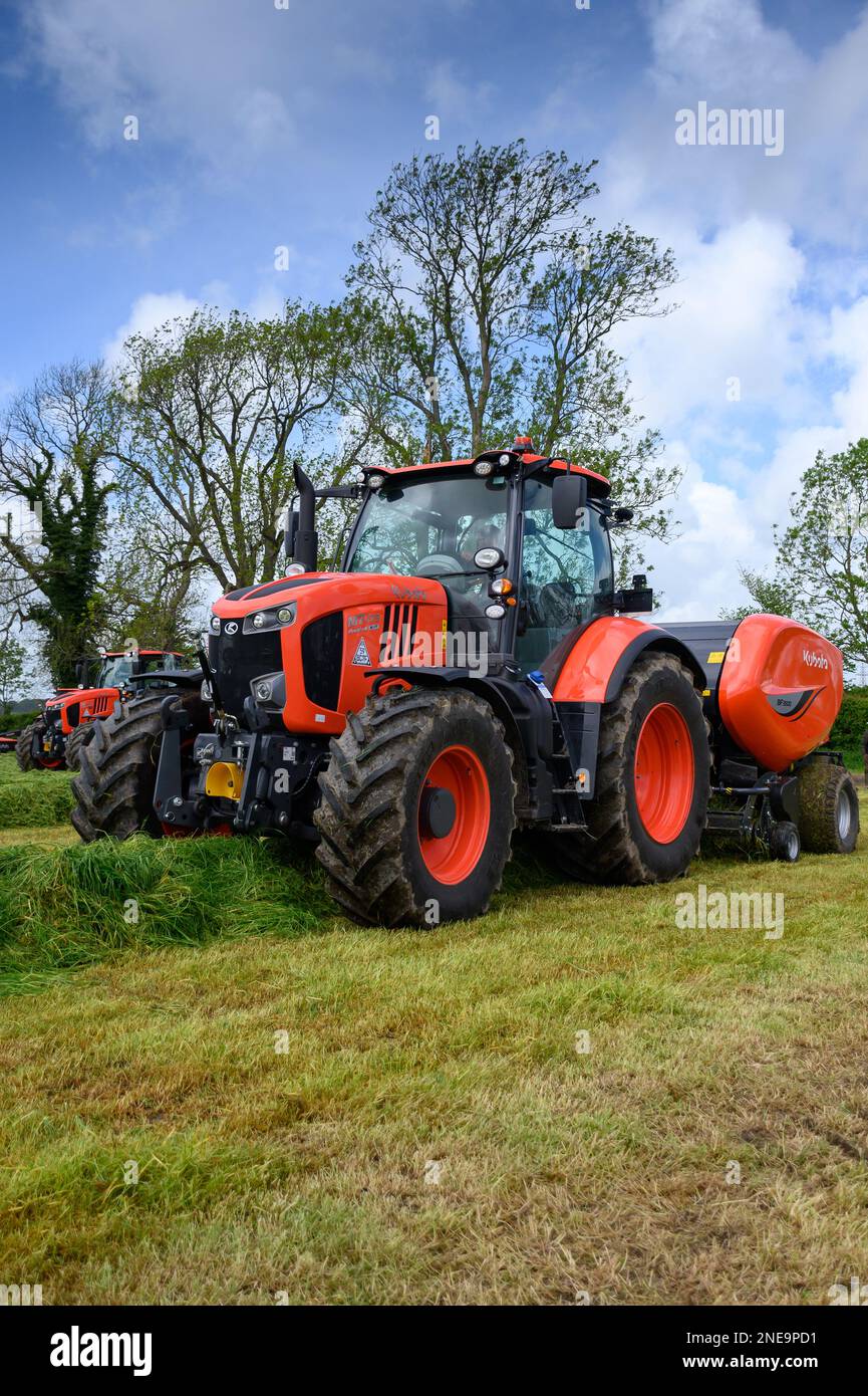 Kuboto M7-173 Premium with round baler making silage bales on a dairy ...