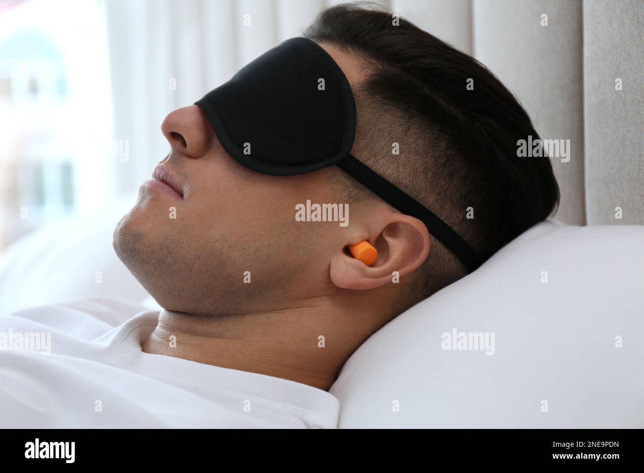 Man with foam ear plugs and mask sleeping in bed, closeup Stock Photo ...