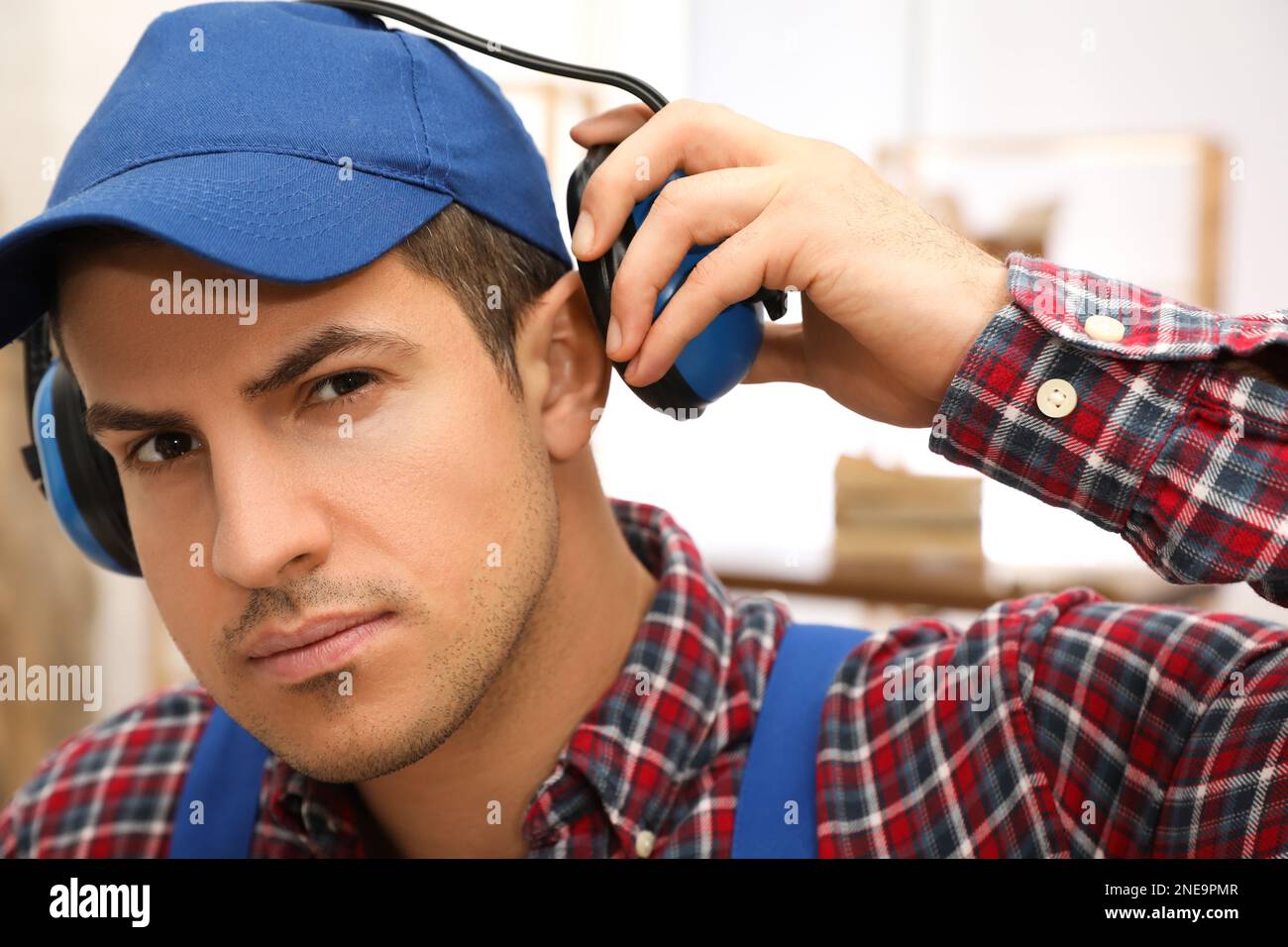 Worker wearing safety headphones indoors. Hearing protection device ...