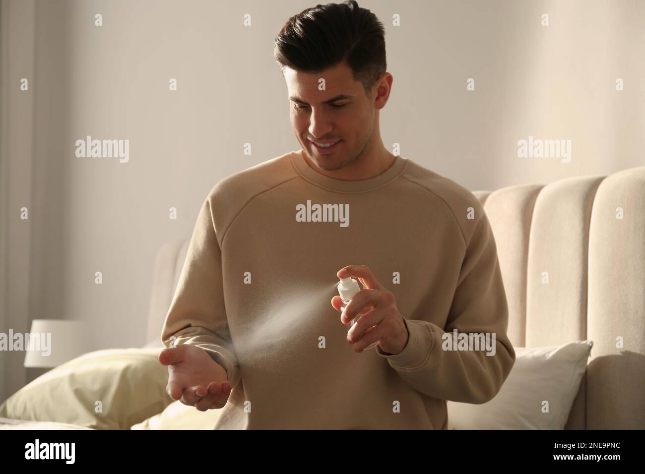 Man applying spray sanitizer onto hand at home Stock Photo - Alamy