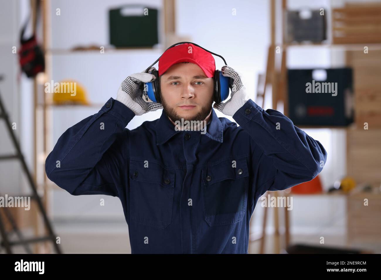 Worker wearing safety headphones indoors. Hearing protection device ...