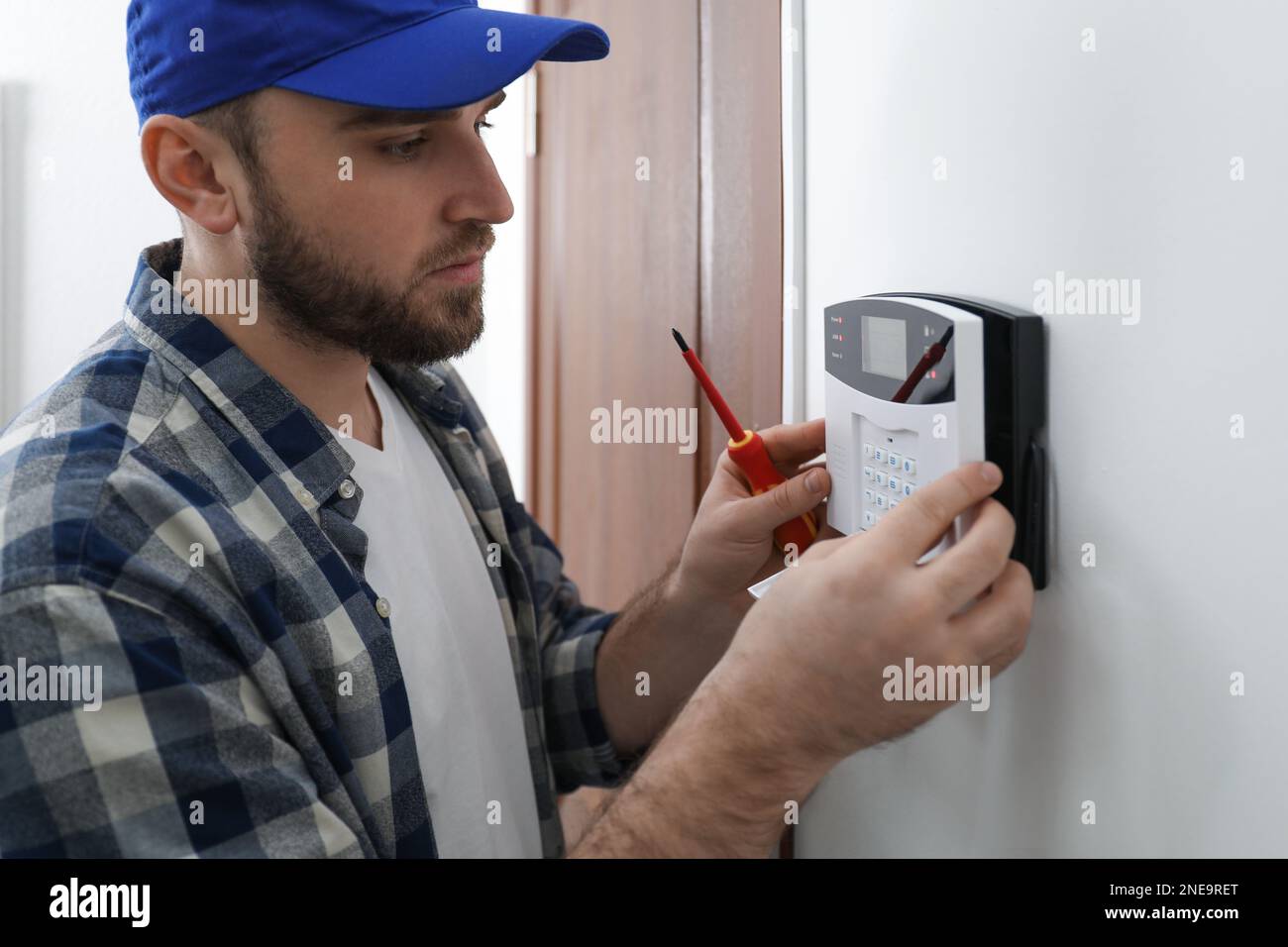 Man installing home security system on white wall in room Stock Photo ...