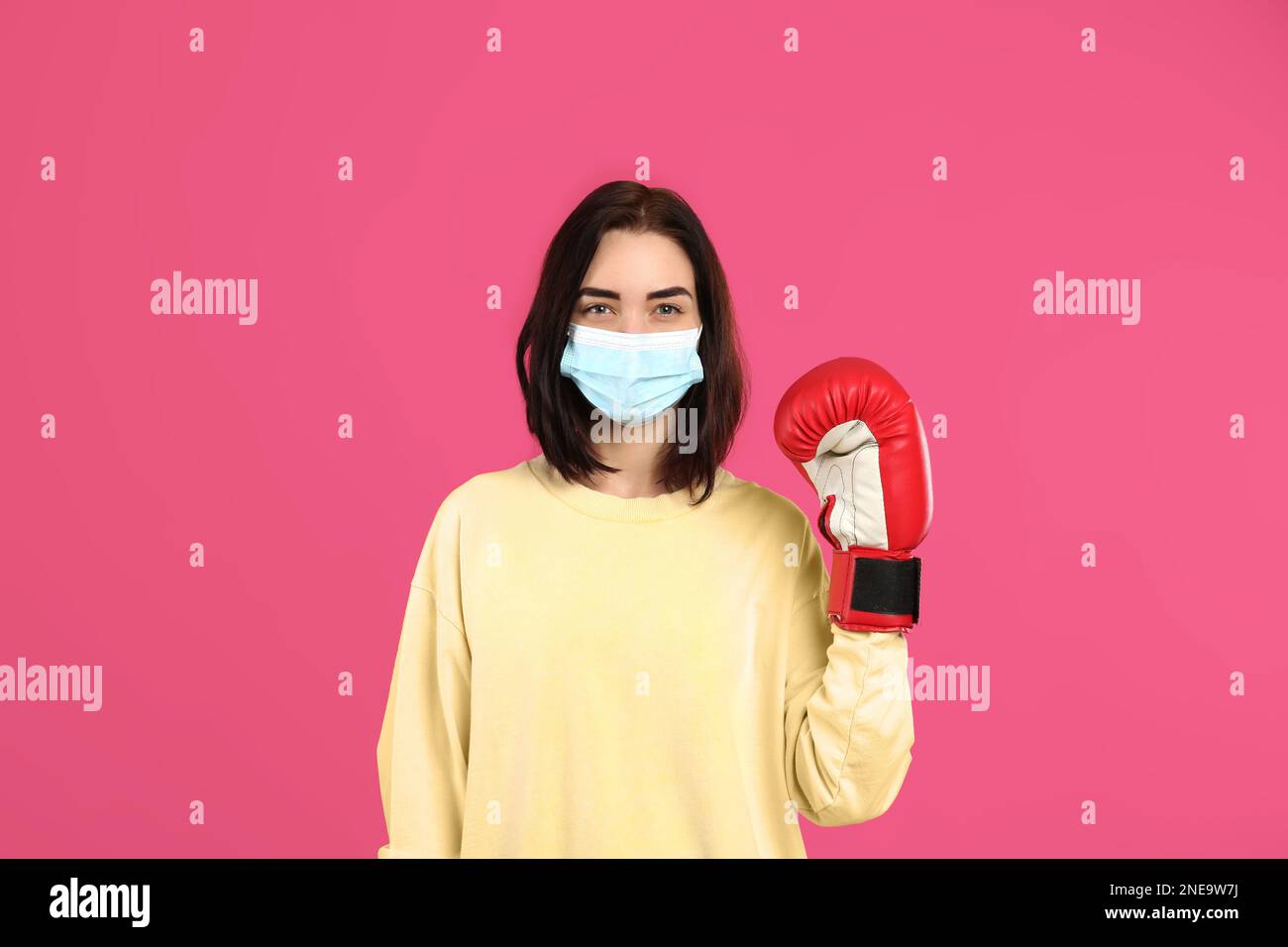 Woman with protective mask and boxing gloves on pink background. Strong ...