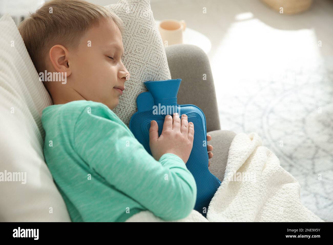 Ill boy with hot water bottle suffering from cold at home Stock Photo ...
