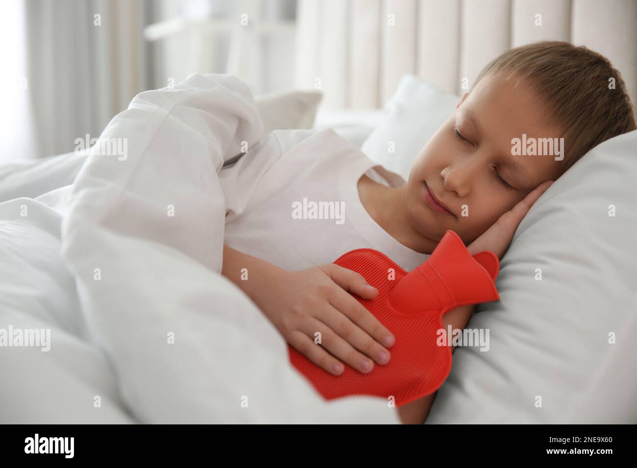 Ill boy with hot water bottle suffering from cold in bed at home Stock ...