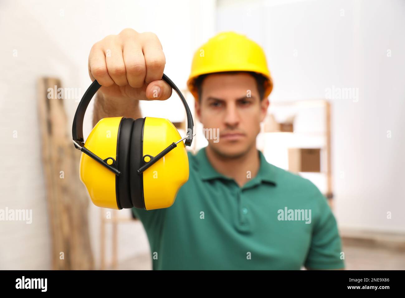 Worker holding safety headphones indoors, focus on device. Hearing ...