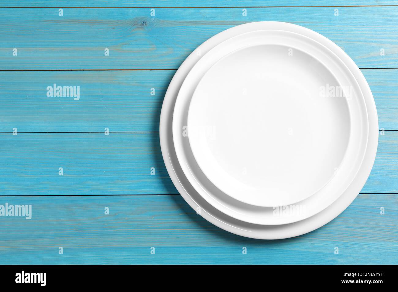 Stack of empty ceramic plates on turquoise wooden table, top view ...