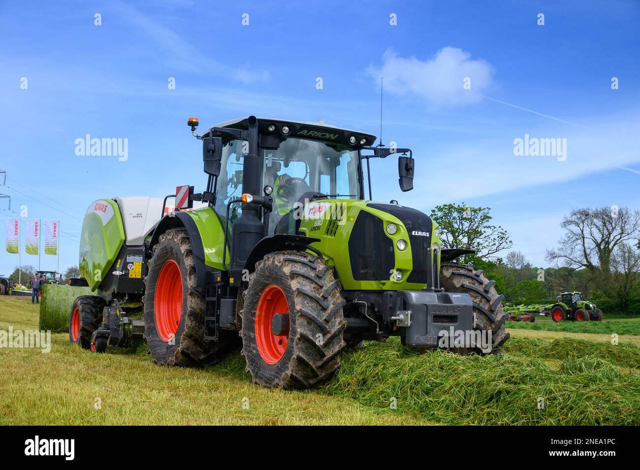 Claas Arion 630 tractor with a round baler making round bales of silage ...