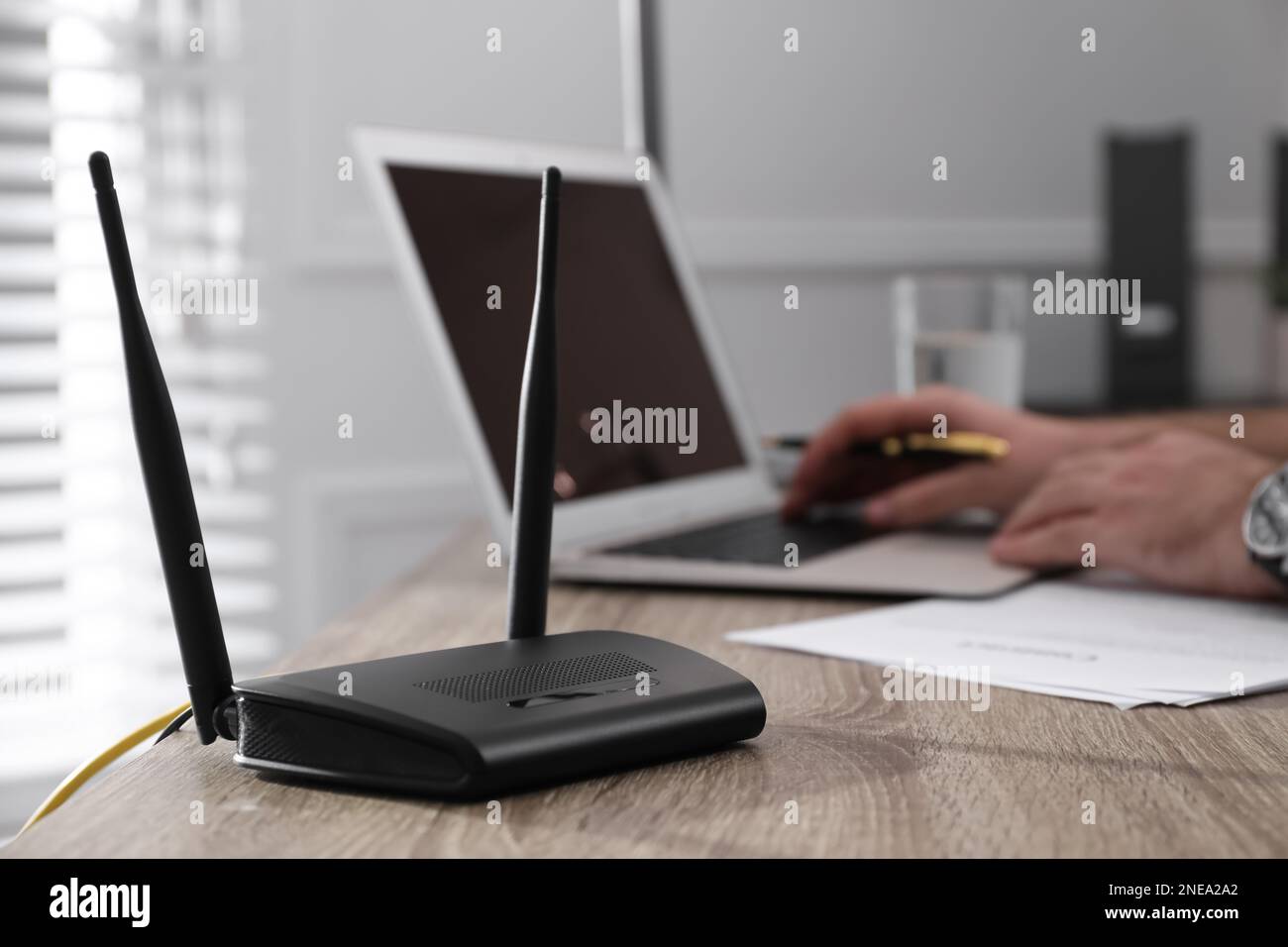Man working with laptop in office, focus on connected router. Wireless ...
