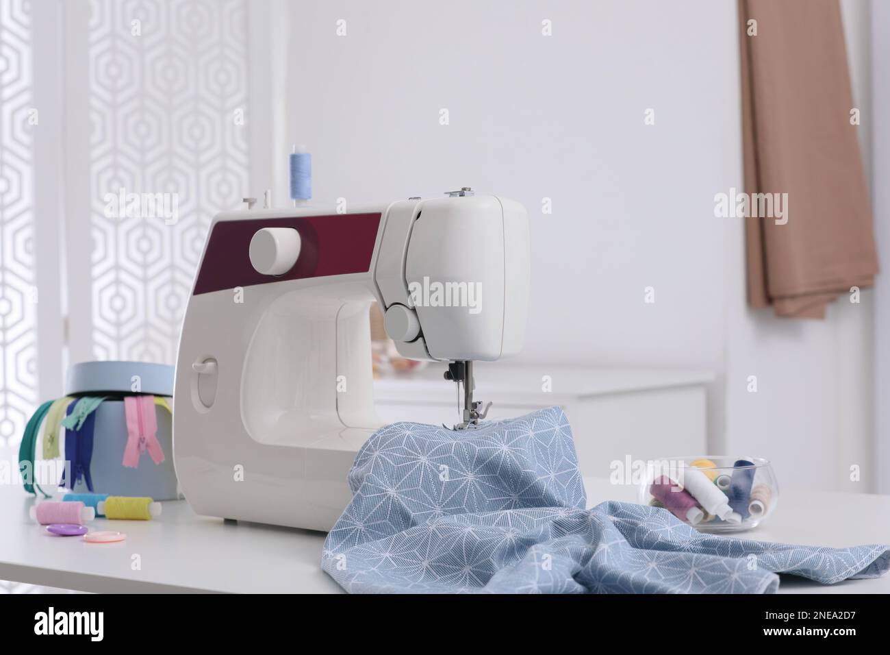 Modern sewing machine, fabric and accessories on table indoors Stock ...