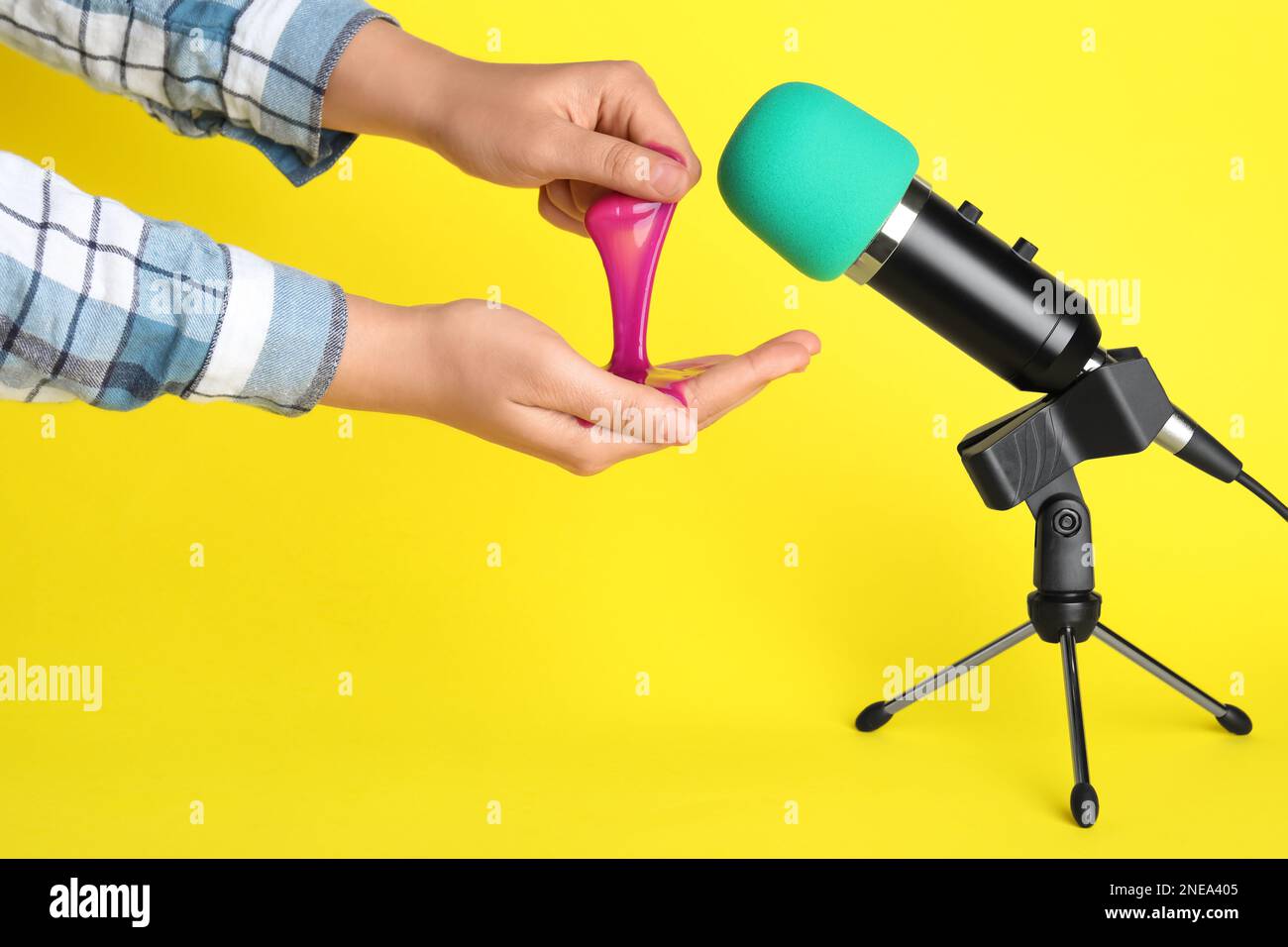 Woman making ASMR sounds with microphone and bright slime on yellow ...
