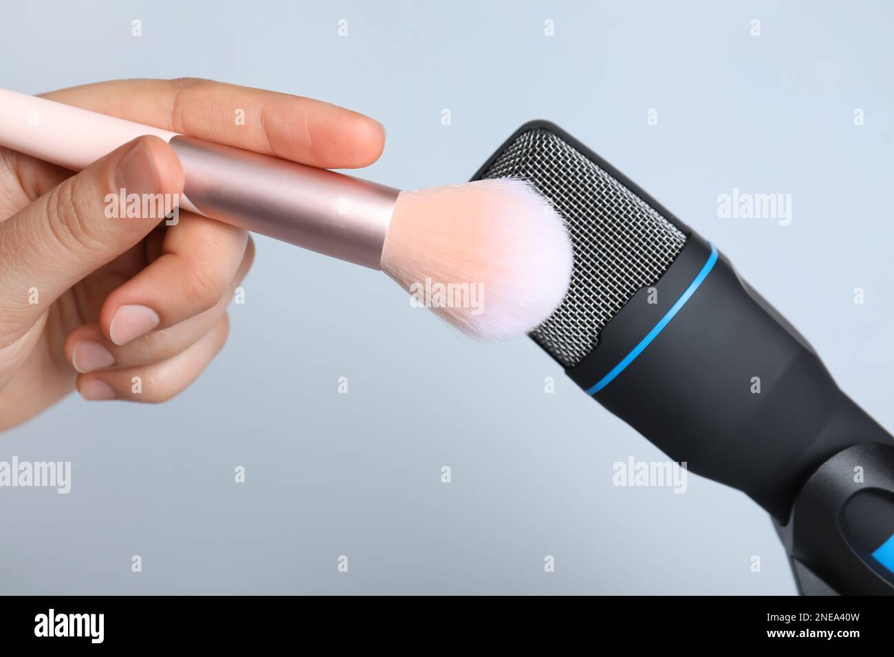 Woman making ASMR sounds with microphone and brush on grey background ...