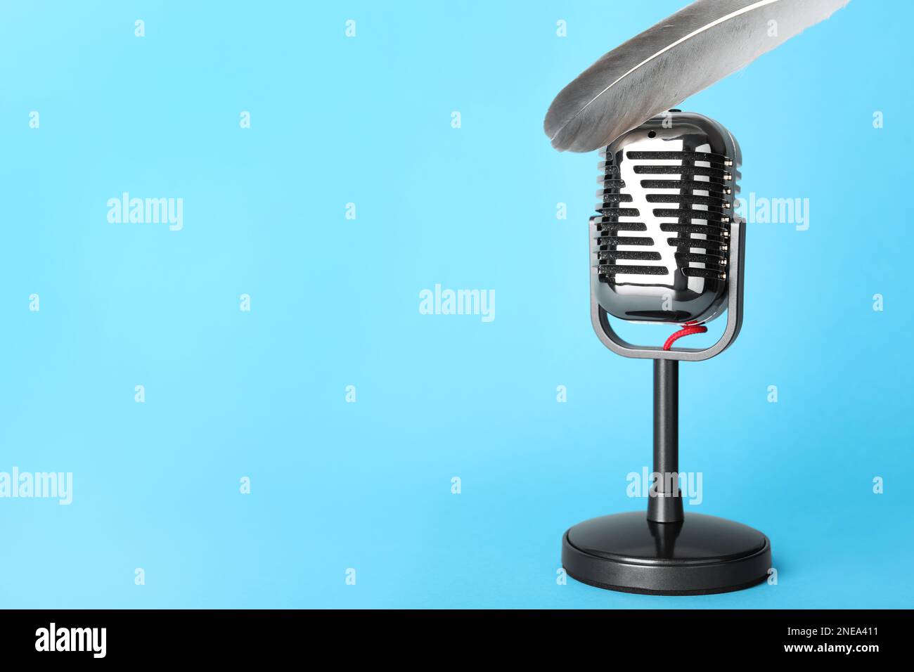 Making ASMR sounds with microphone and feather on light blue background ...