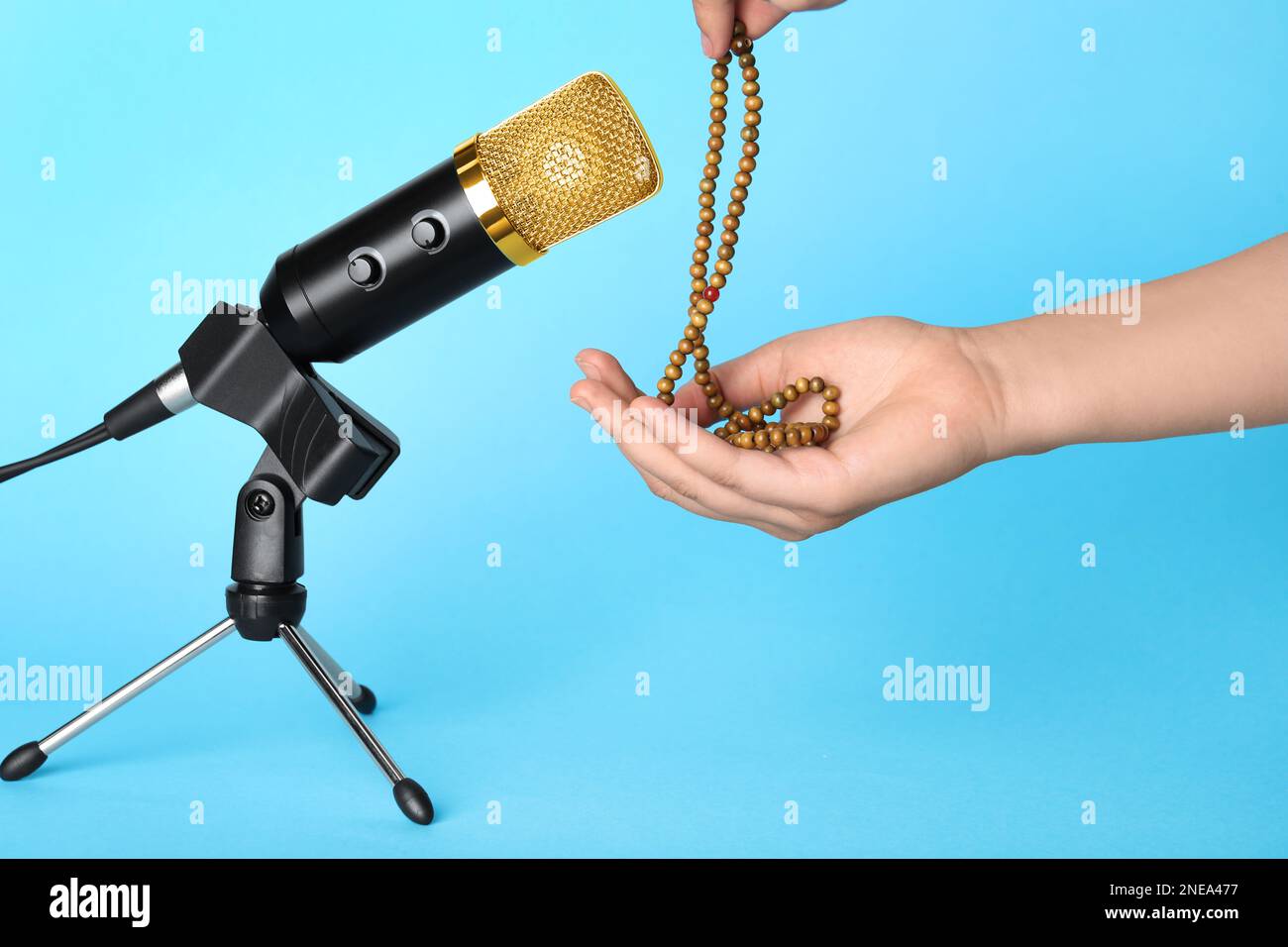 Woman making ASMR sounds with microphone and beads on light blue ...