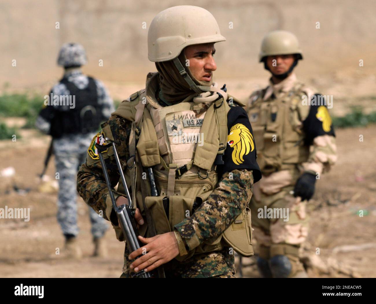A Kurdish Peshmerga, center, stands guard with an Iraqi policeman, left ...