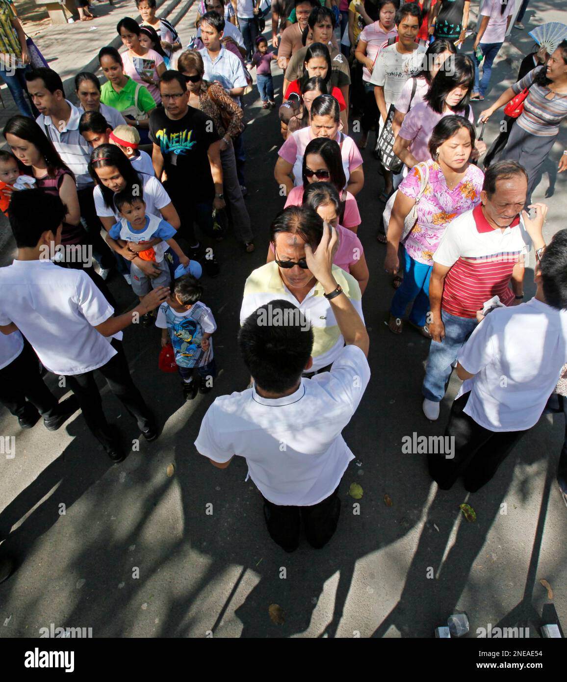 Filipino Catholics line up to have their foreheads applied with ash or ...