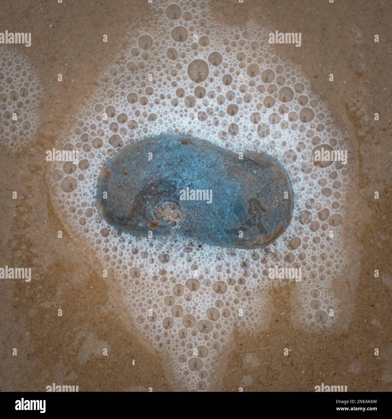 Beautiful blue stone surrounded by water foam. Sea, sand, beach in ...