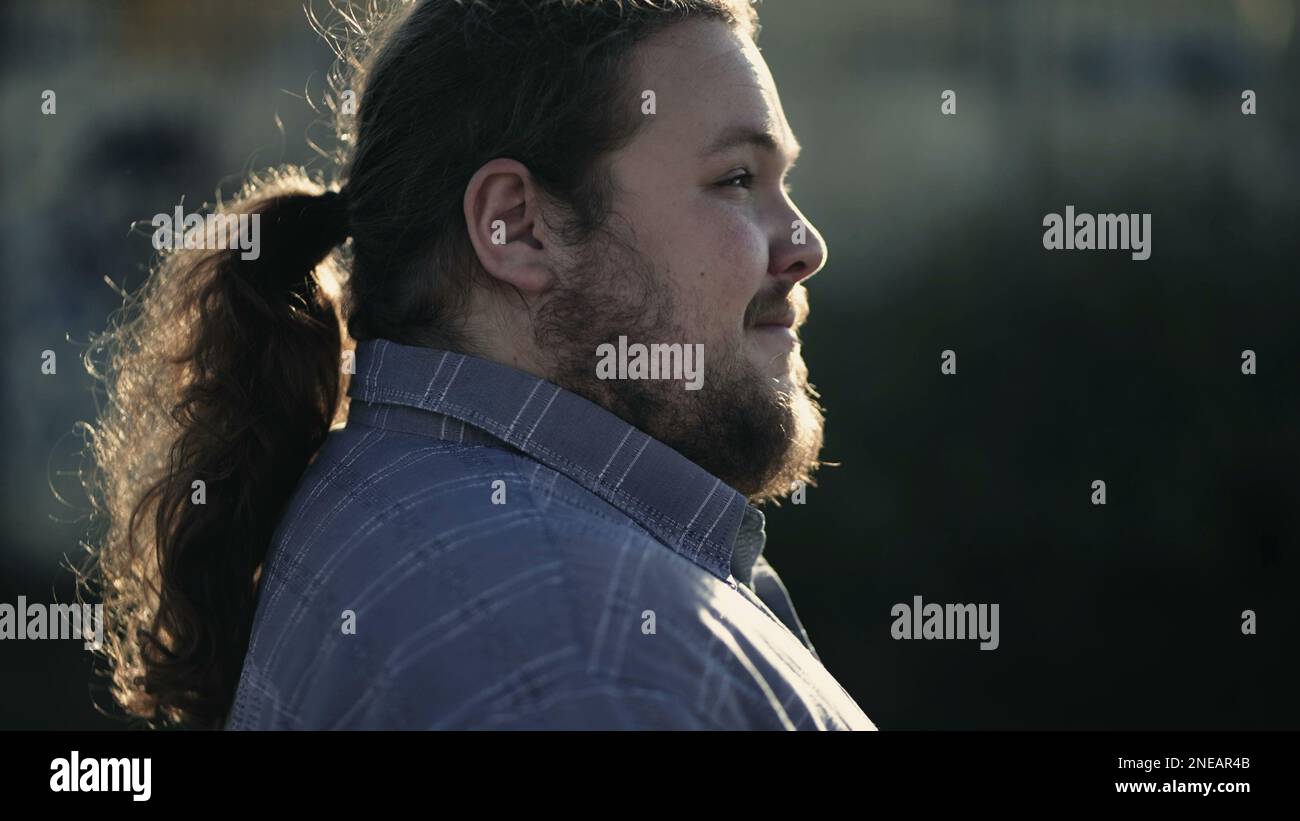 Happy person walking outdoors. Contemplative expression of a young ...