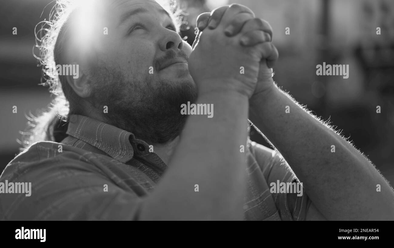 Hopeful young man praying to God outside having FAITH in monochromatic ...