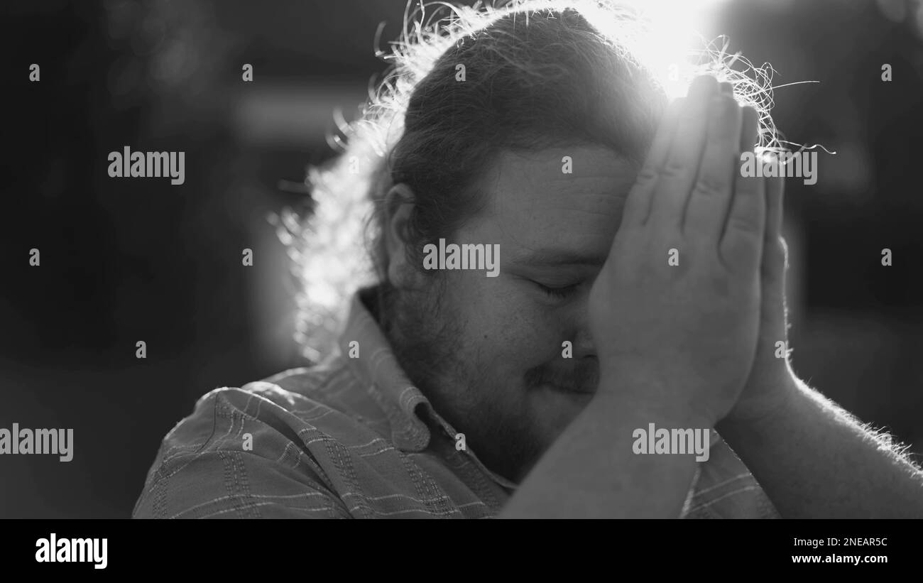 Hopeful young man praying to God outside having FAITH in monochromatic ...