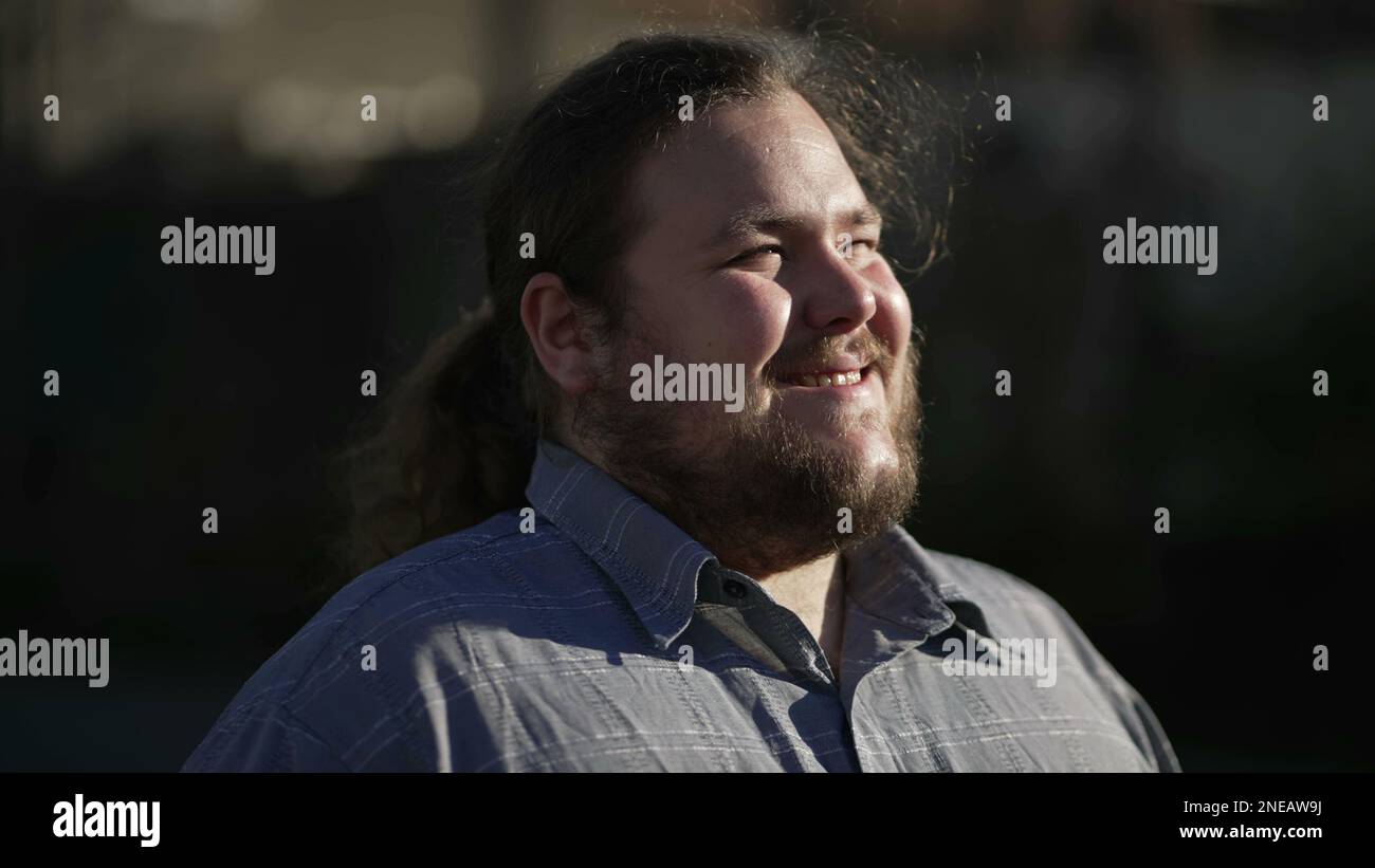 One meditative young man standing outside turning head to sky smiling ...