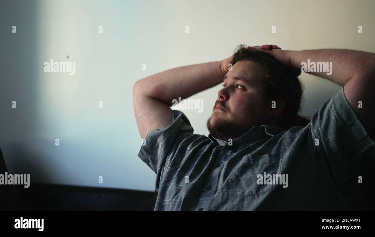 One pensive overweight young man thinking deeply at home. Thoughtful ...