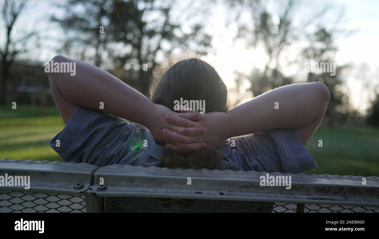 Back of a relaxed young man sitting at park bench enjoying nature and ...