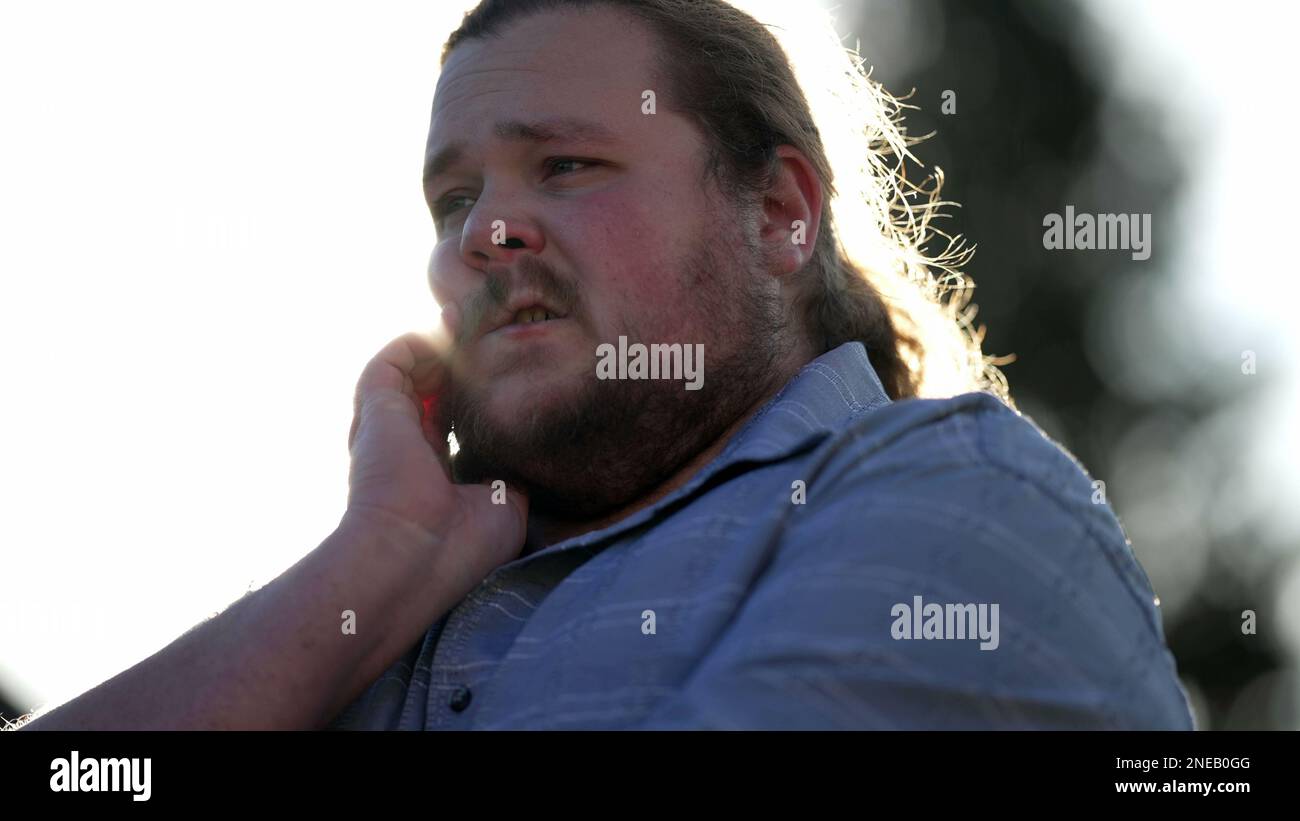 Frustrated young man feeling anxiety and worry standing outdoors in ...