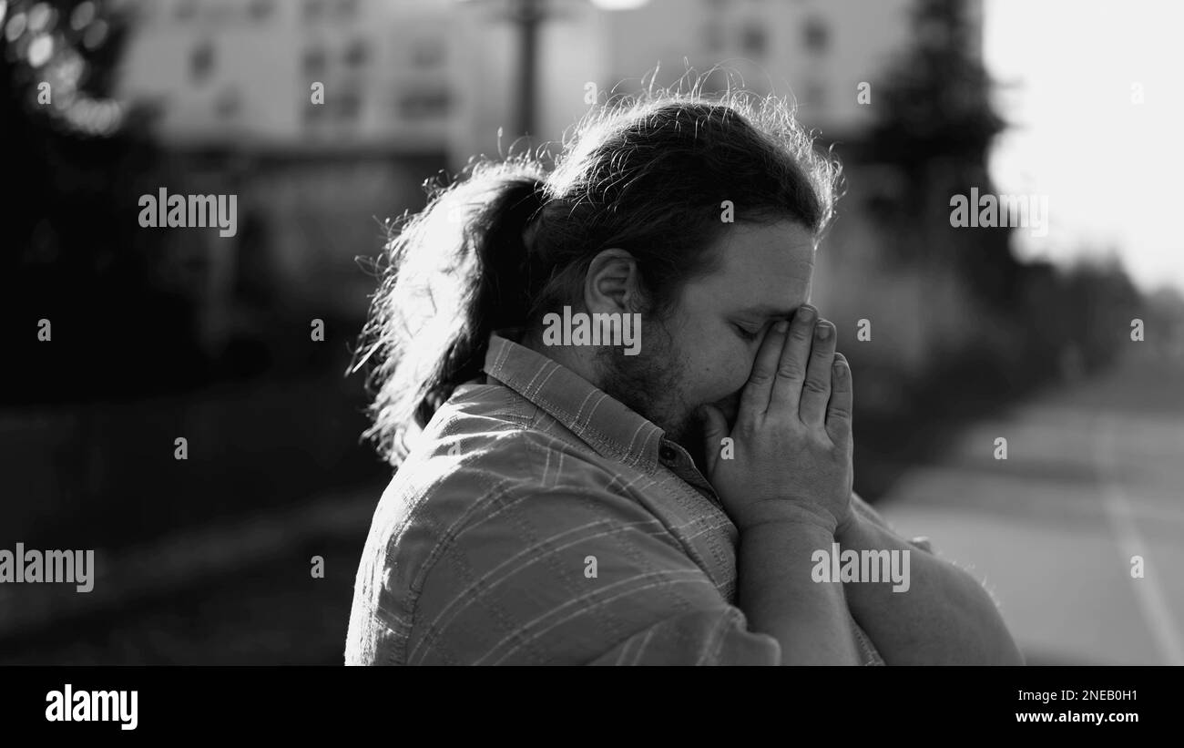 Desperate person standing outside covering face in shame. Anxious ...