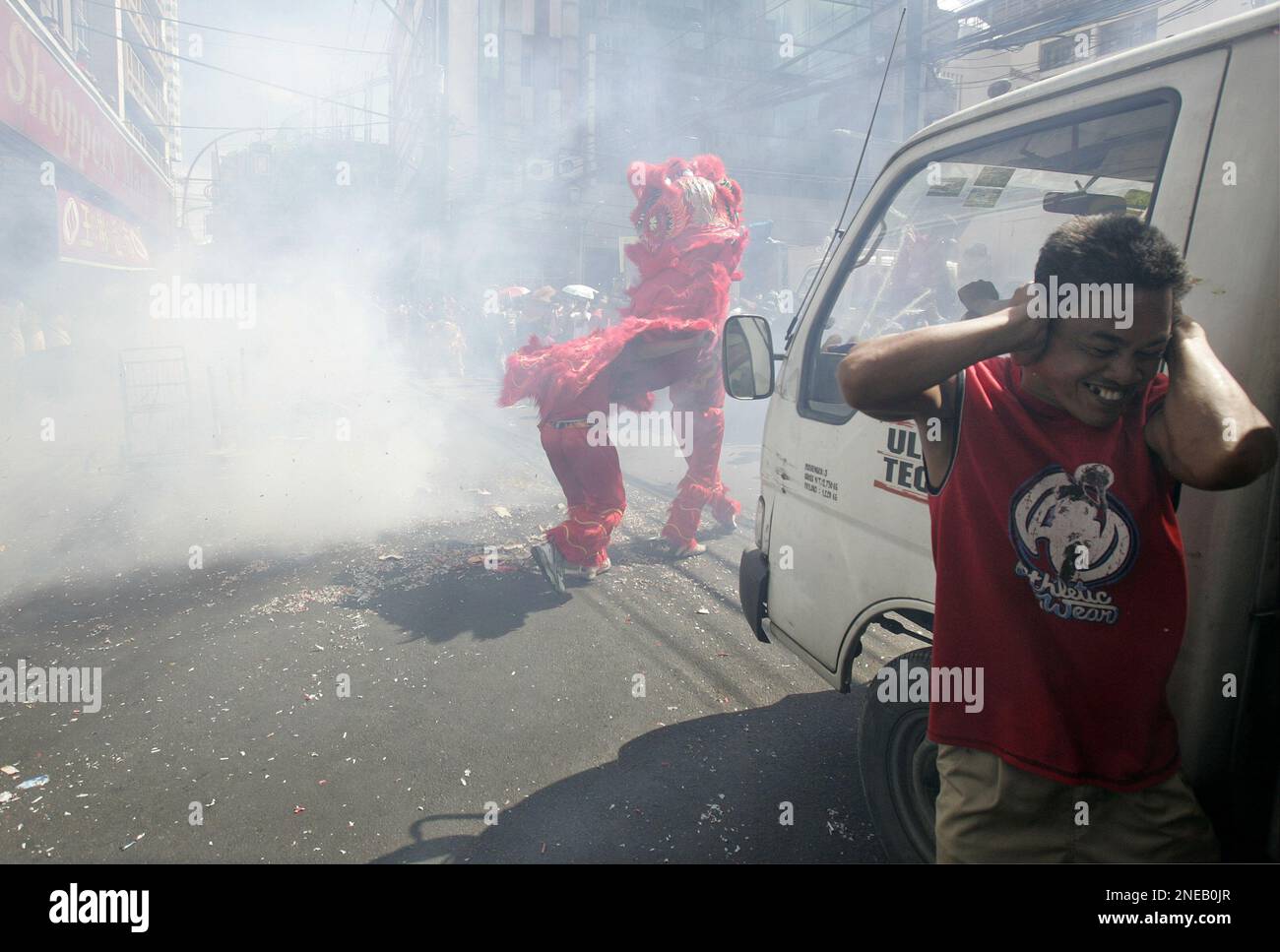 A Filipino man covers his ears as firecrackers explode during a lion dance performance in Manila ...