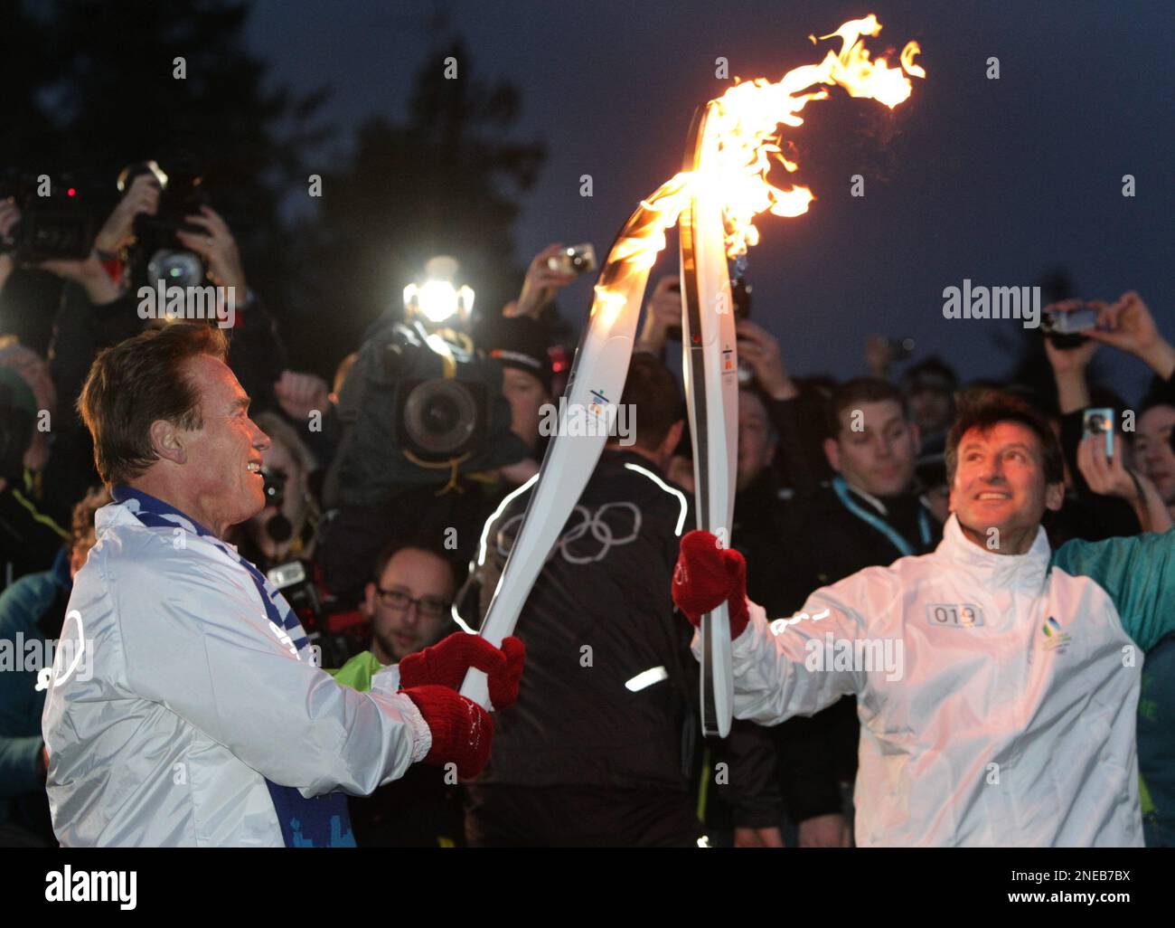 California Gov.Arnold Schwarzenegger, left, passes the Olympic flame to ...