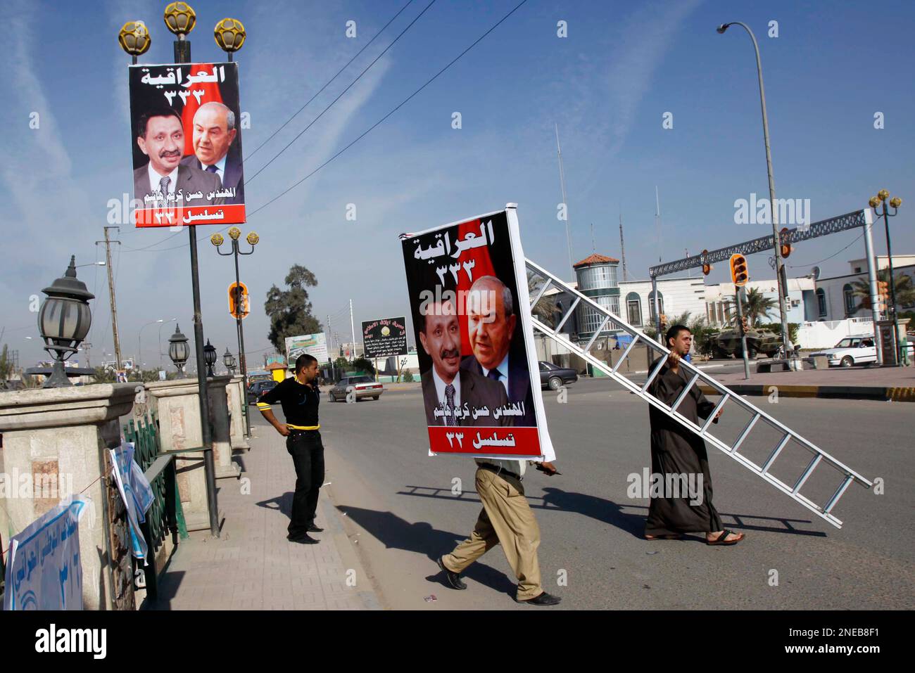 Workers install a campaign poster for candidate Hassan Karim Hashem ...