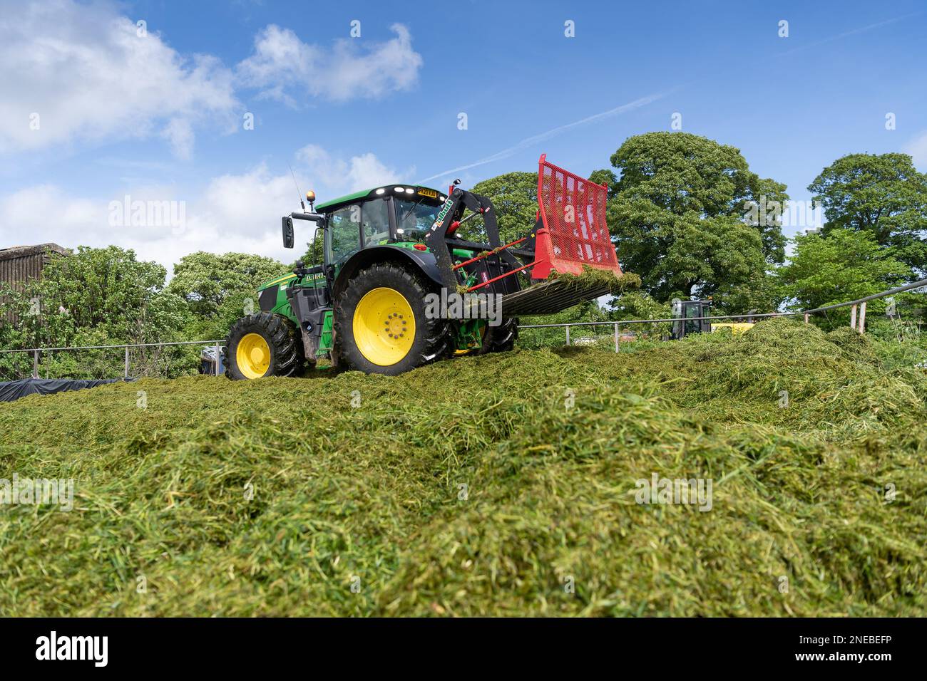John Deere 6215R with a rear mounted buckrake working on a silage pit ...
