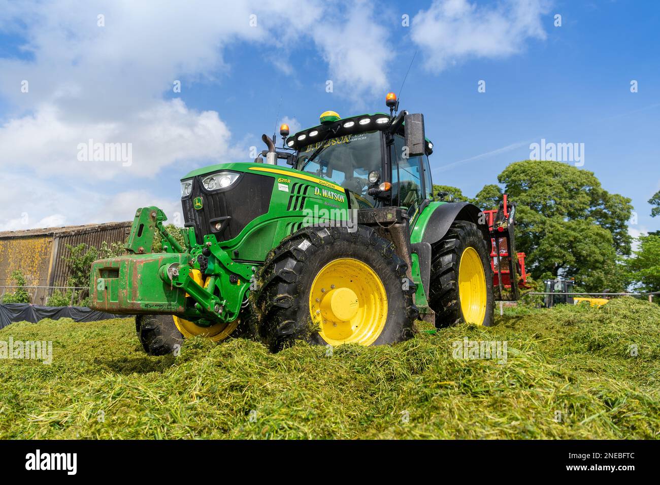John Deere 6215R with a rear mounted buckrake working on a silage pit ...