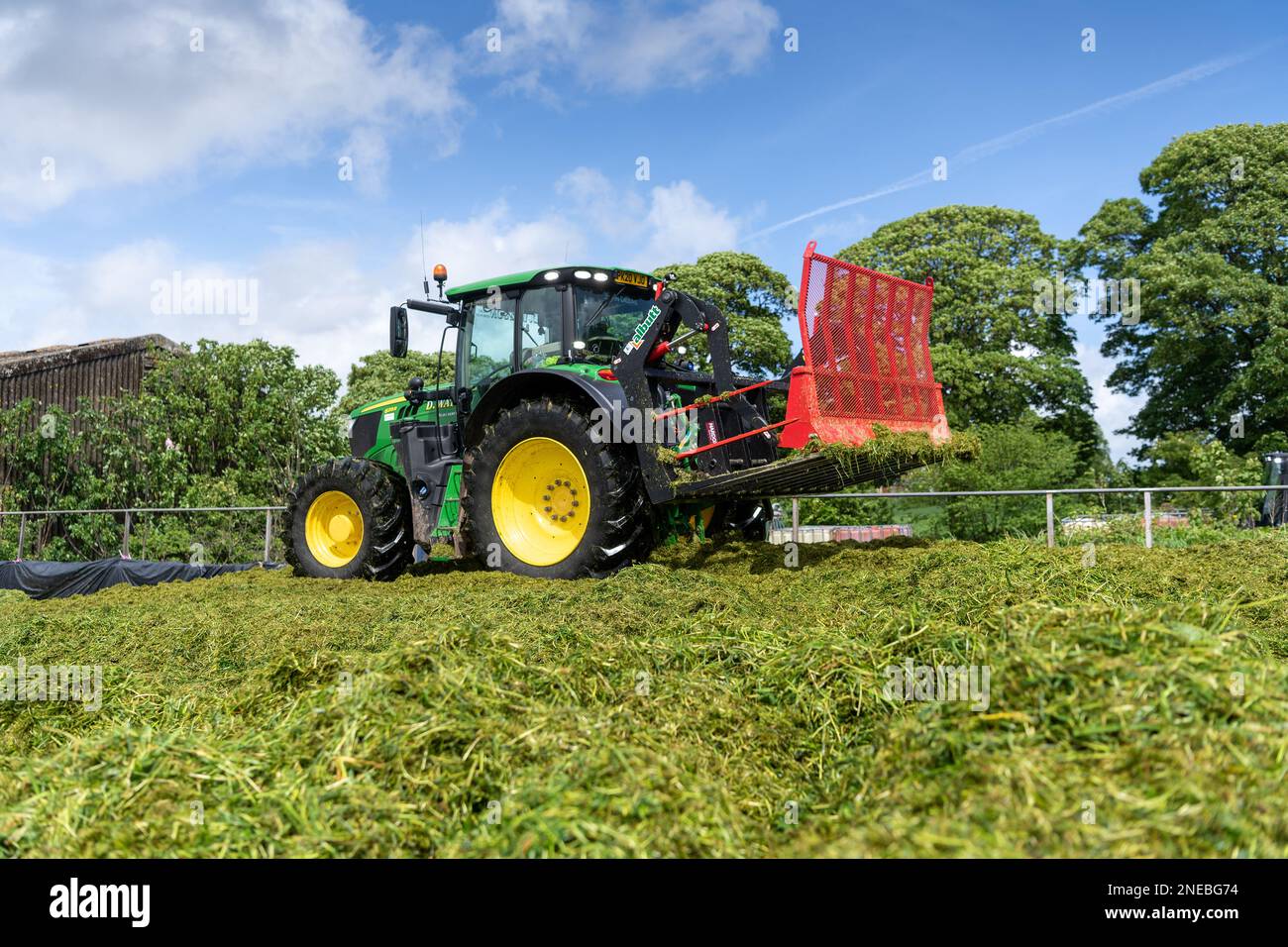 John Deere 6215R with a rear mounted buckrake working on a silage pit ...