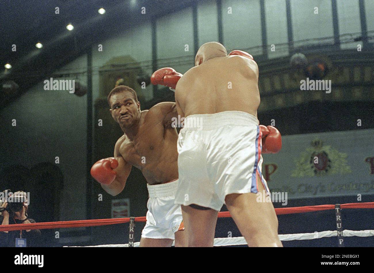 Evander Holyfield, left, delivers a punch as George Foreman covers up ...
