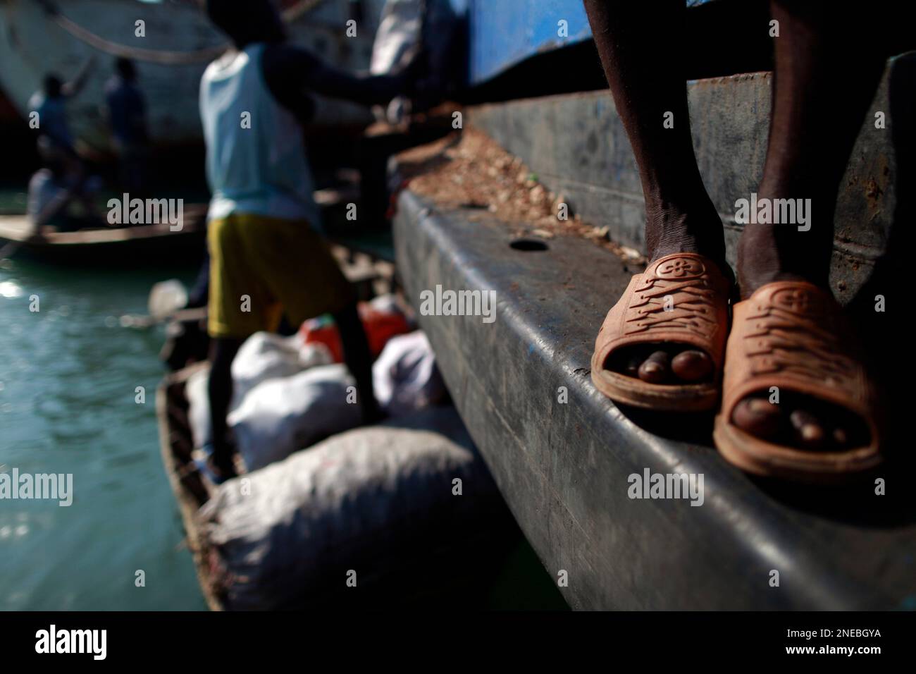 Men unload charcoal bags brought by boat from the eastern town of ...