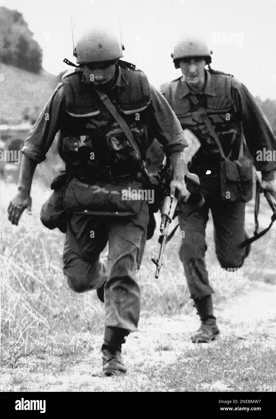 Yugoslav army soldiers run to secure the safe landing of a helicopter ...