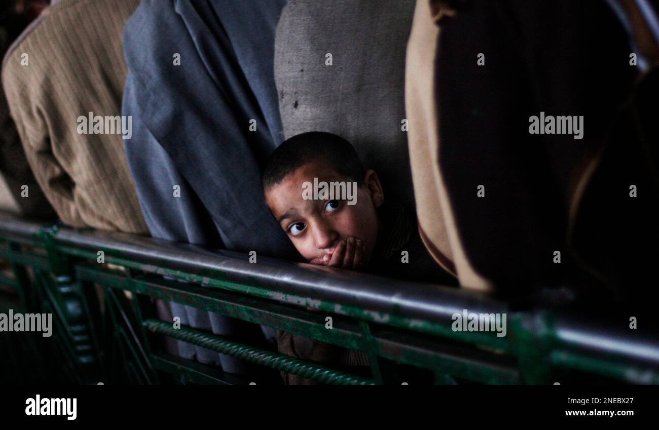 A Pakistani boy eats rice as he lines up with other men to get a ration ...