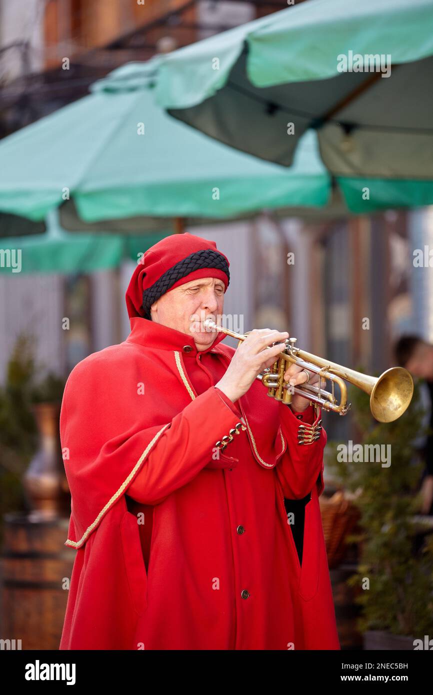 Medieval trumpeter in red cloak. People in ancient authentic clothes of ...