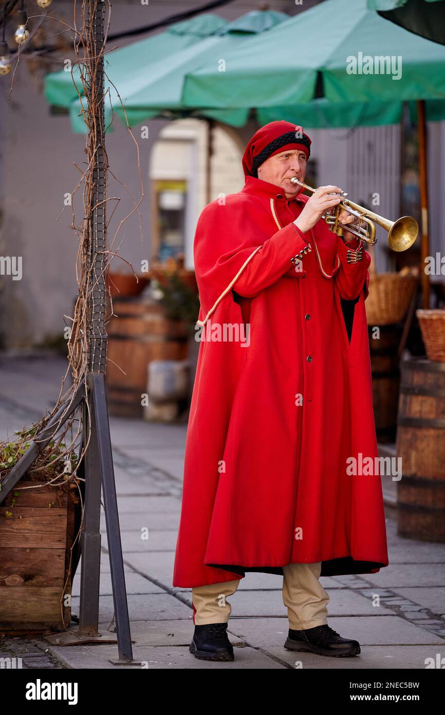 Medieval trumpeter in red cloak. People in ancient authentic clothes of ...