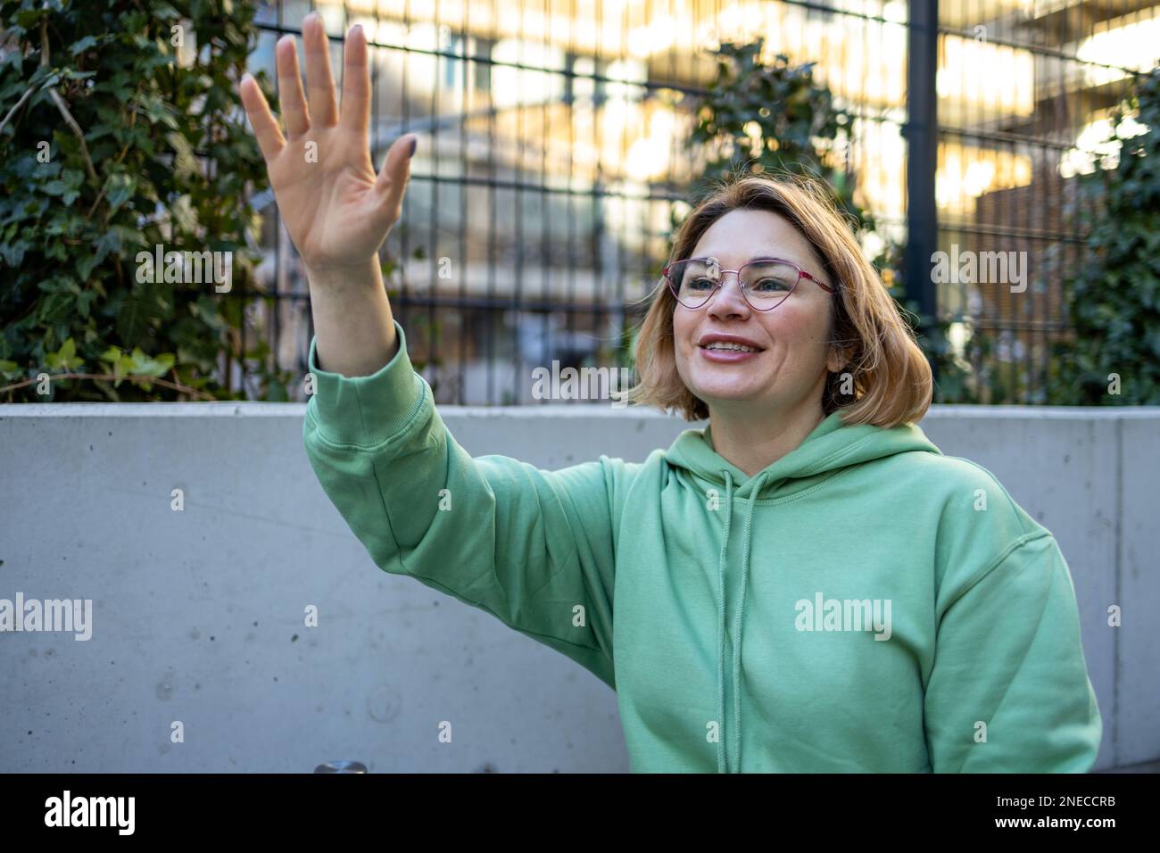 Blond middle aged women waving outside to somebody with her hand Stock ...