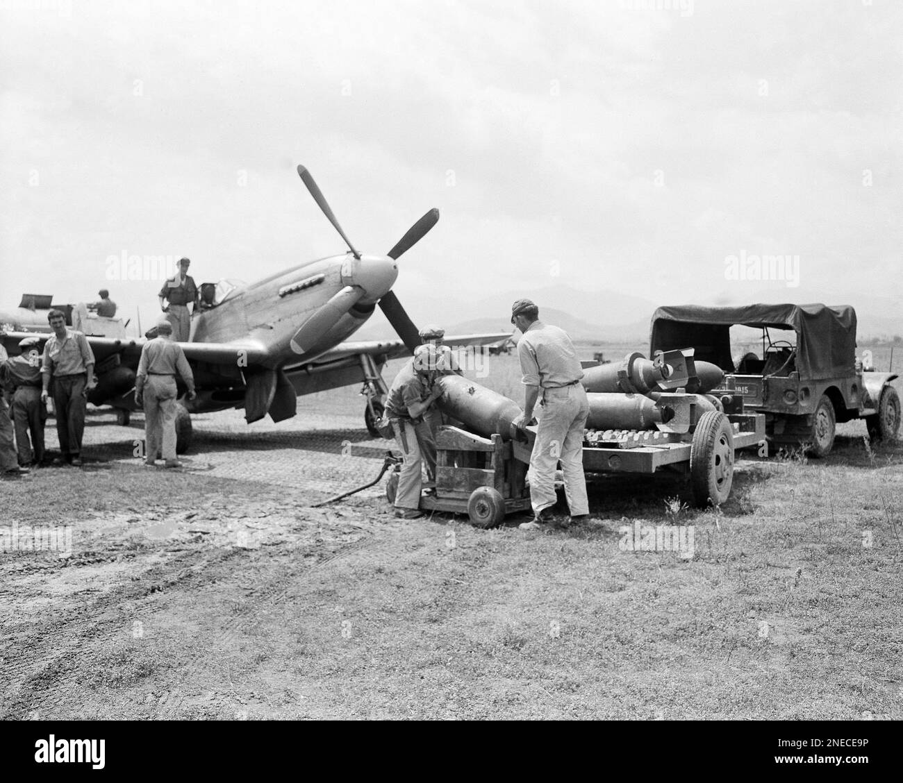 A ground crew carefully handles 500-pound explosive bomb to be attached ...
