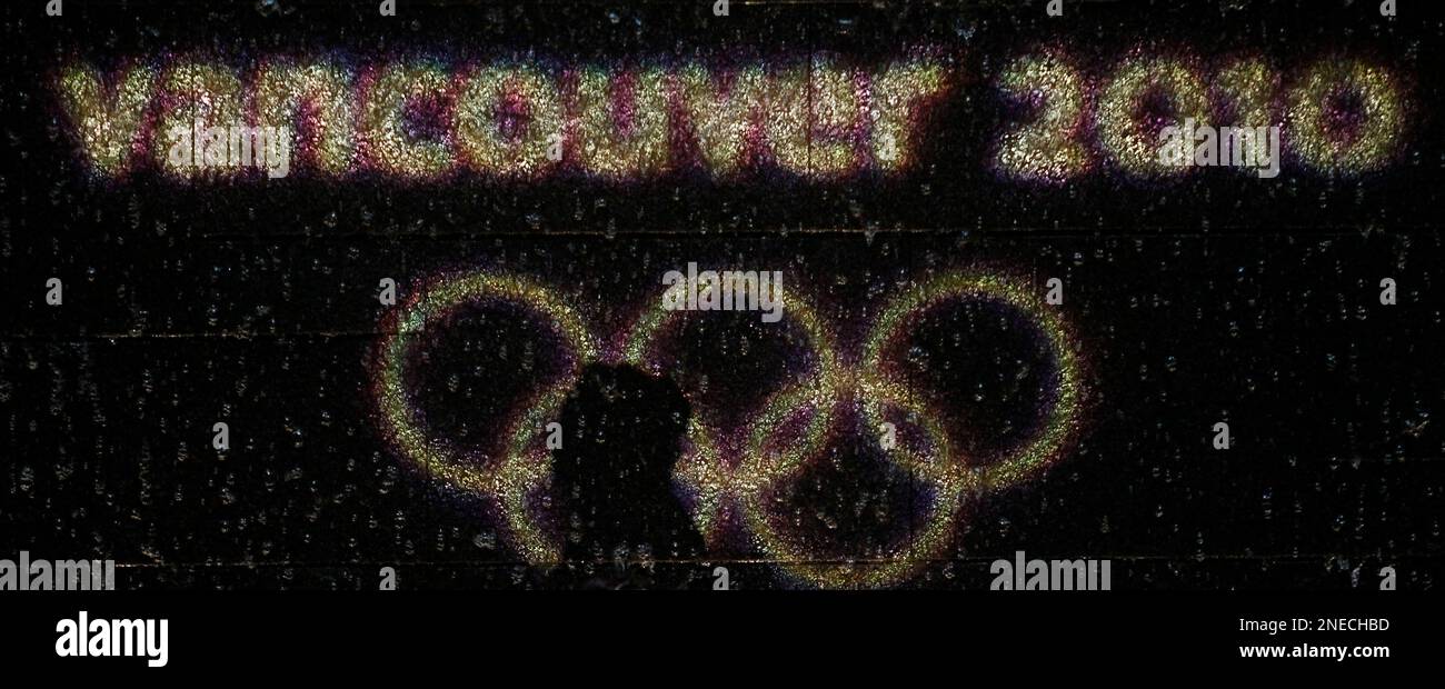A woman casts a shadow on a projection of the Olympic rings on a ...