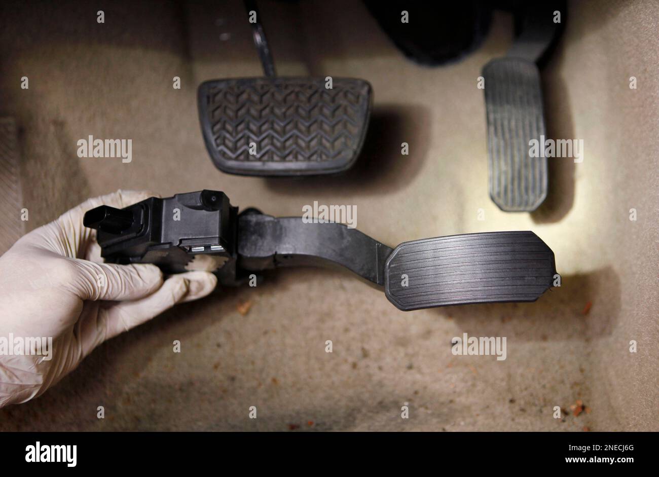 A recalled Toyota gas pedal is shown next to a recalled Toyota Avalon ...