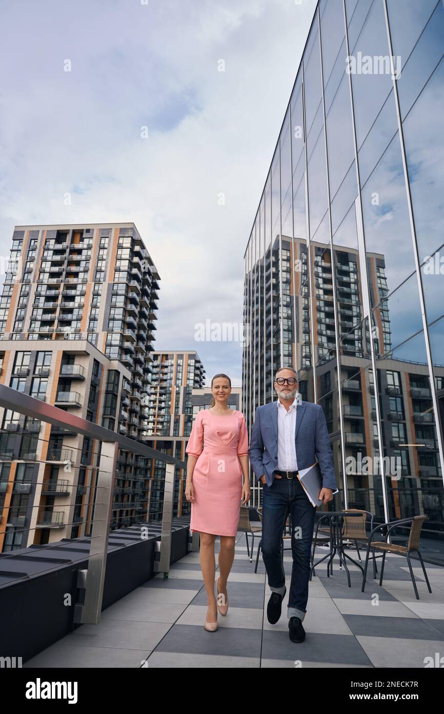 Colleagues in stylish office clothes walk along the spacious terrace ...