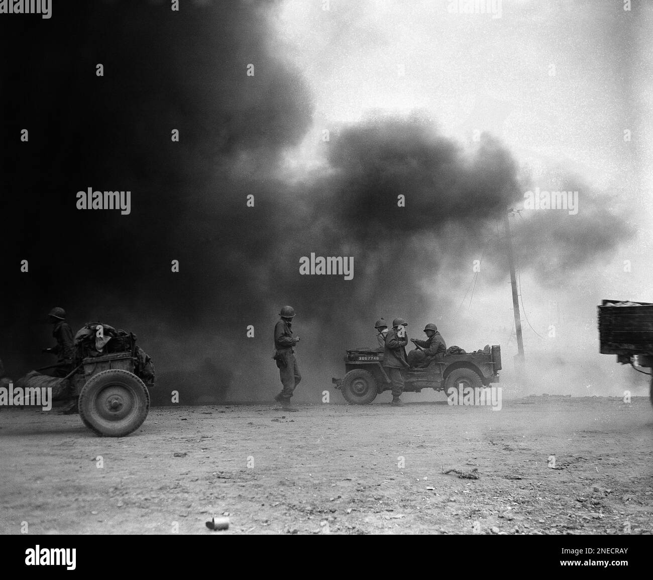 American soldiers start to take cover after an ammunition dump explodes ...