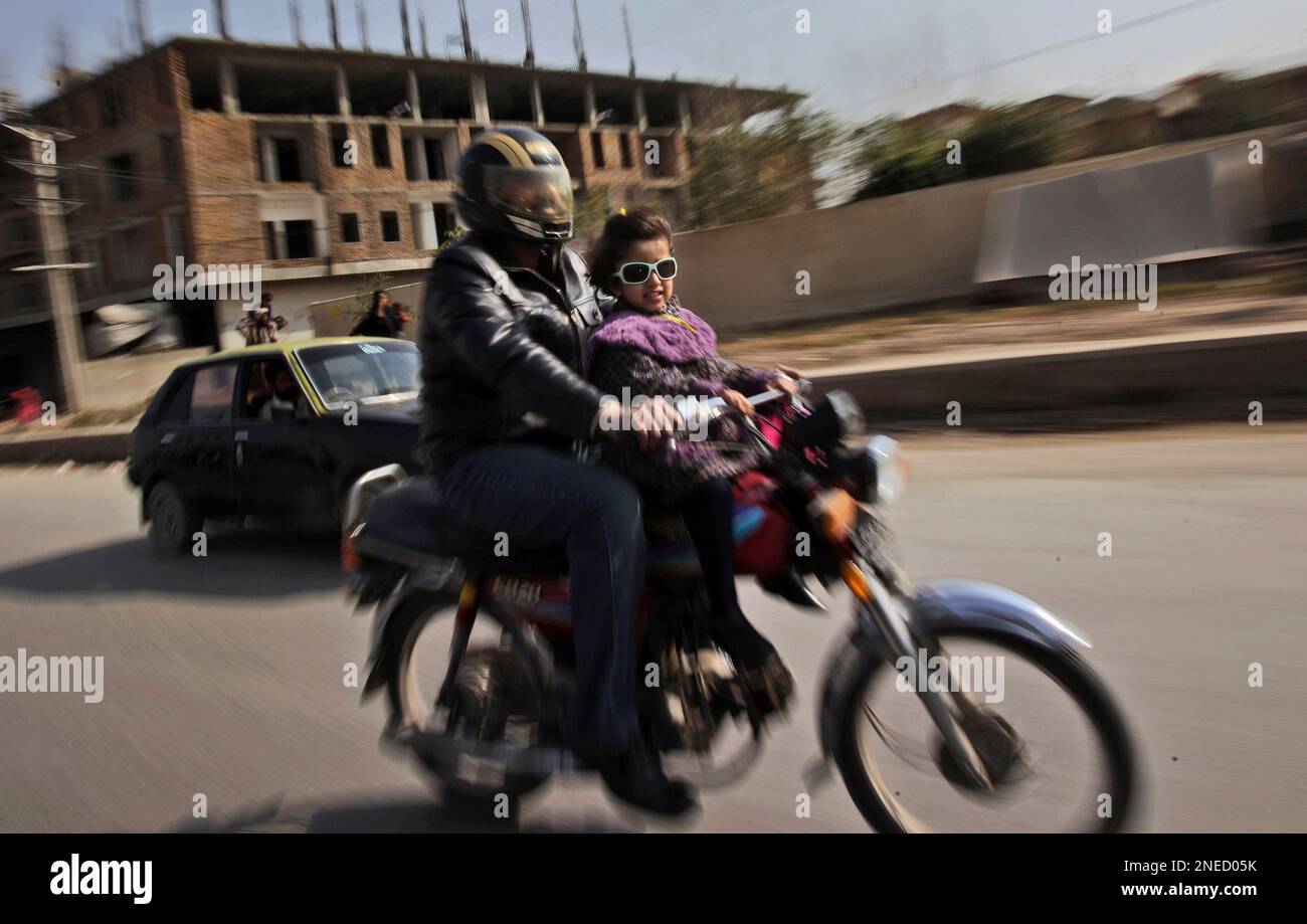 A young Pakistani girl looks on while riding a motorcycle, on the ...