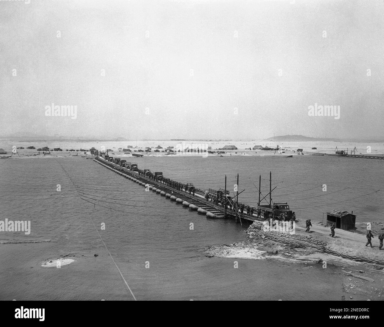 A long column of UN troops and supply vehicles move over pontoon bridge ...